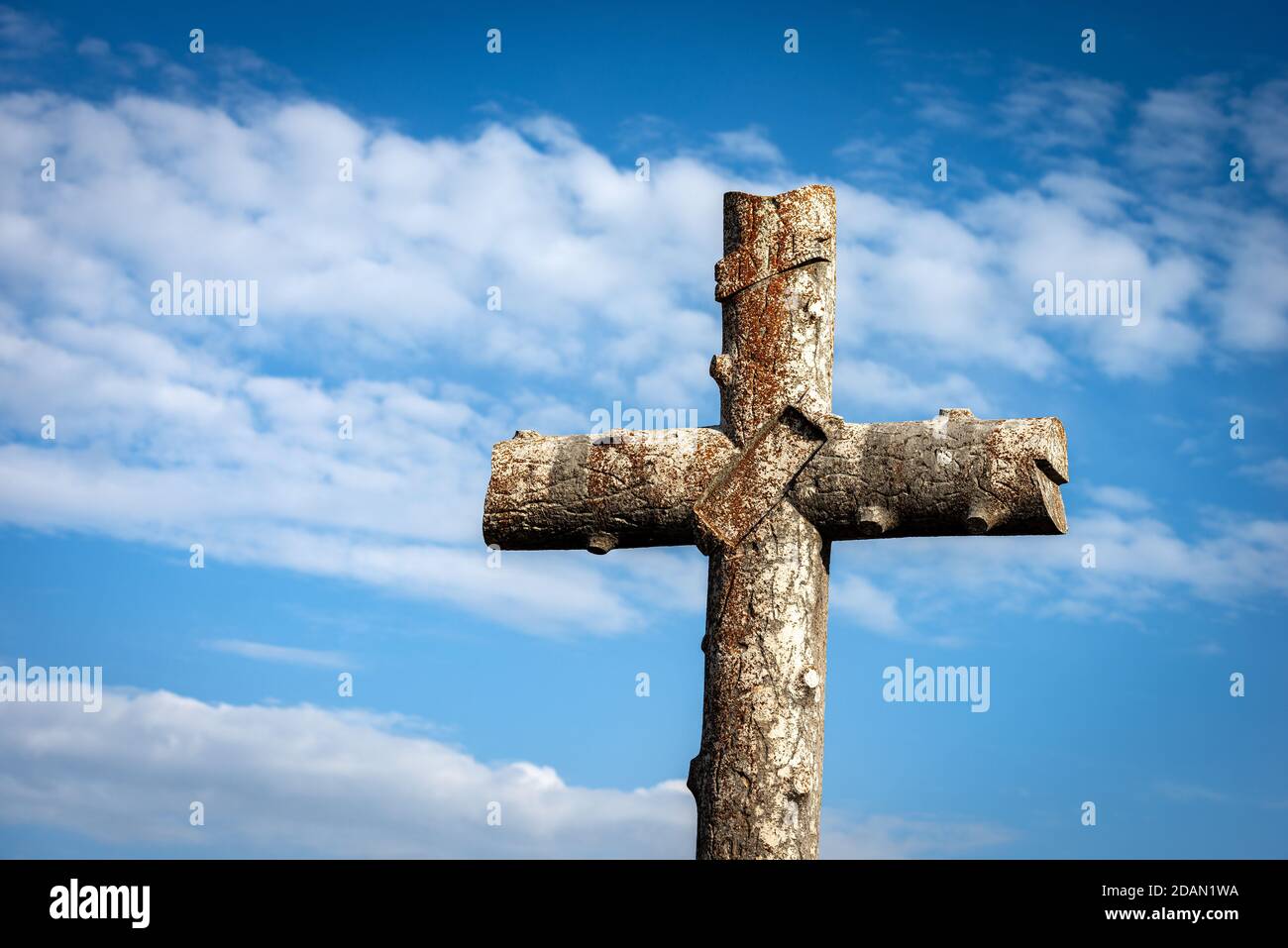 Ancient christian cross made of stone on blue sky with clouds ...