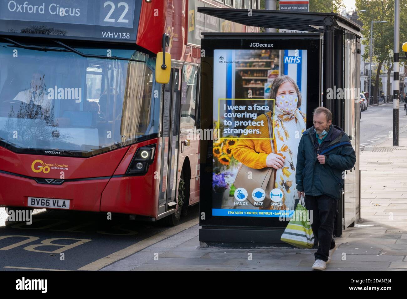 Shoppers walk past an NHS (National Health Service) bus shelter ad on ...
