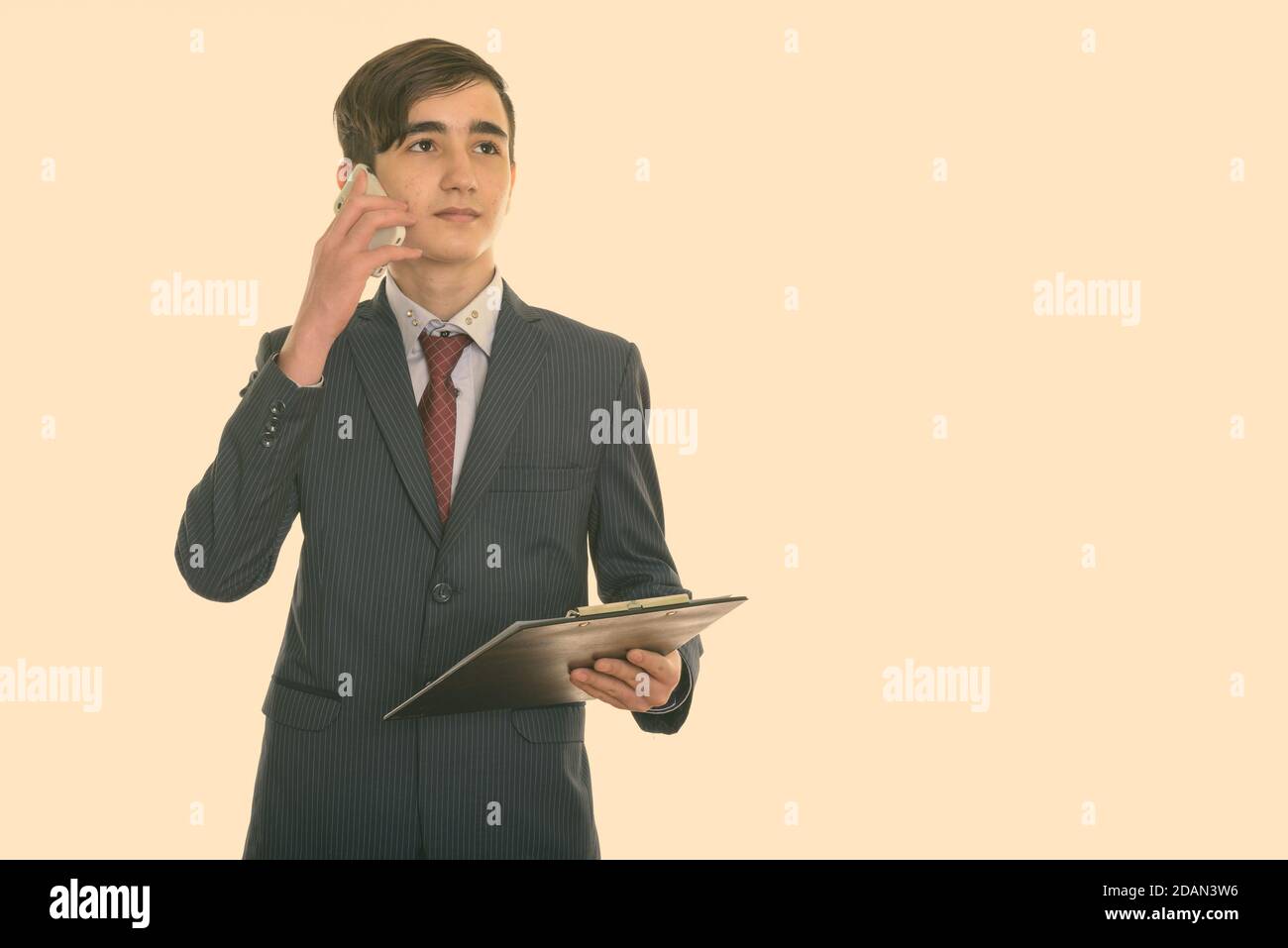 Studio shot of young handsome Persian teenage businessman thinking ...