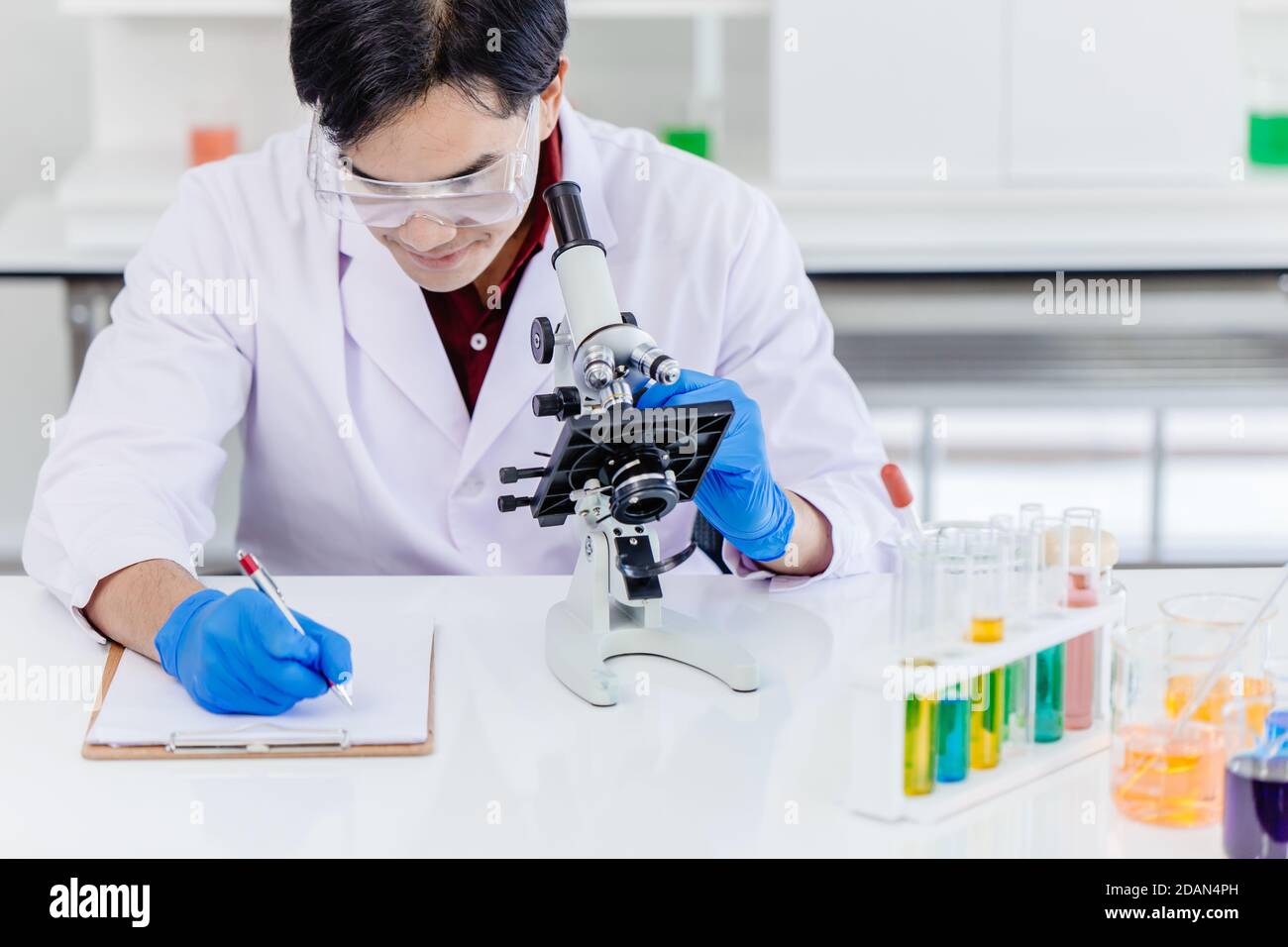 Asian male scientist working at laboratory desk with medical sample ...