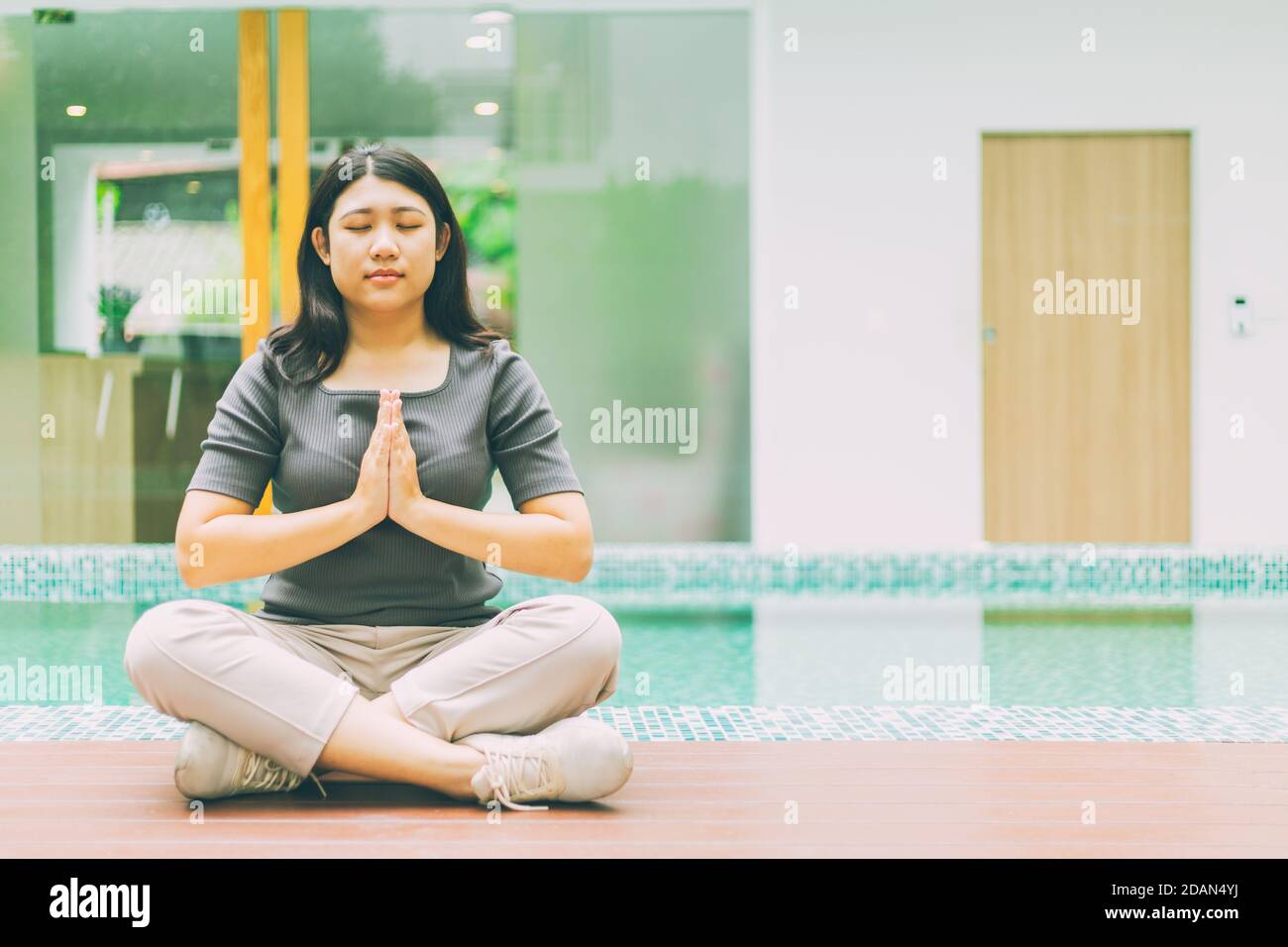 Asian female doing yoga sitting in a lotus hand posture at home ...