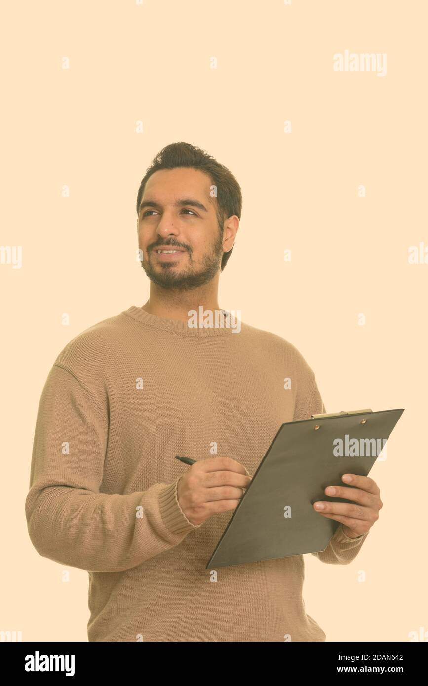 Young happy Indian man writing report on clipboard while thinking Stock ...