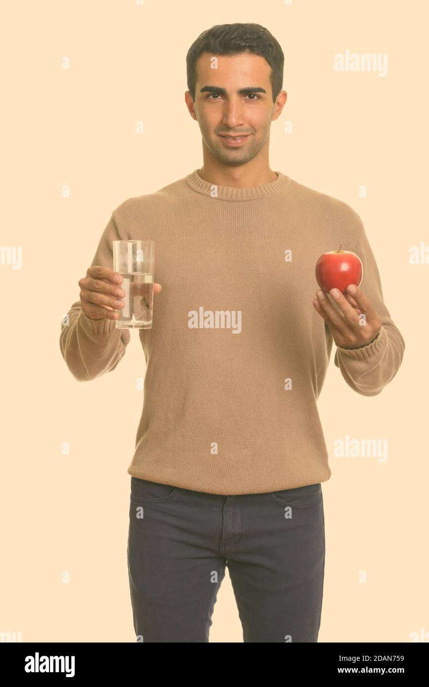 Young happy Iranian man holding red apple and glass of water Stock ...