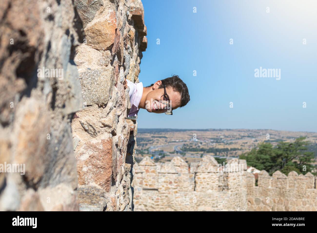 young boy sticking his head out of a part of the castle wall in a sunny ...