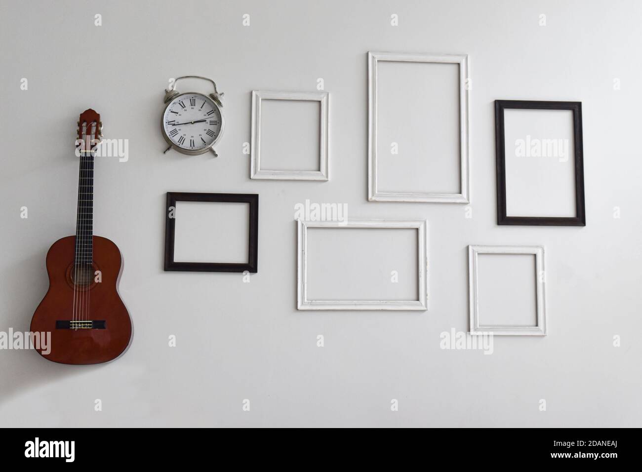 Blank picture frames, clock and guitar on white cement wall Stock Photo ...