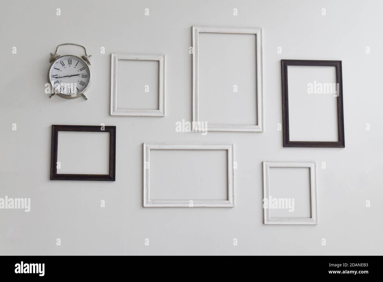 Blank picture frames and clock on white cement wall Stock Photo - Alamy