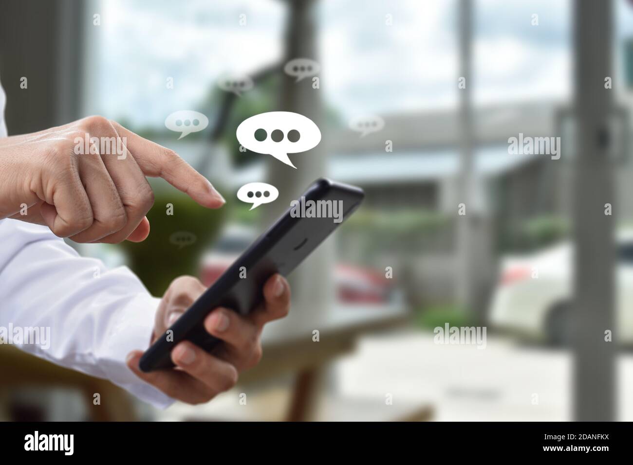 Hand using mobile phone typing, with chat icons. Social media and ...