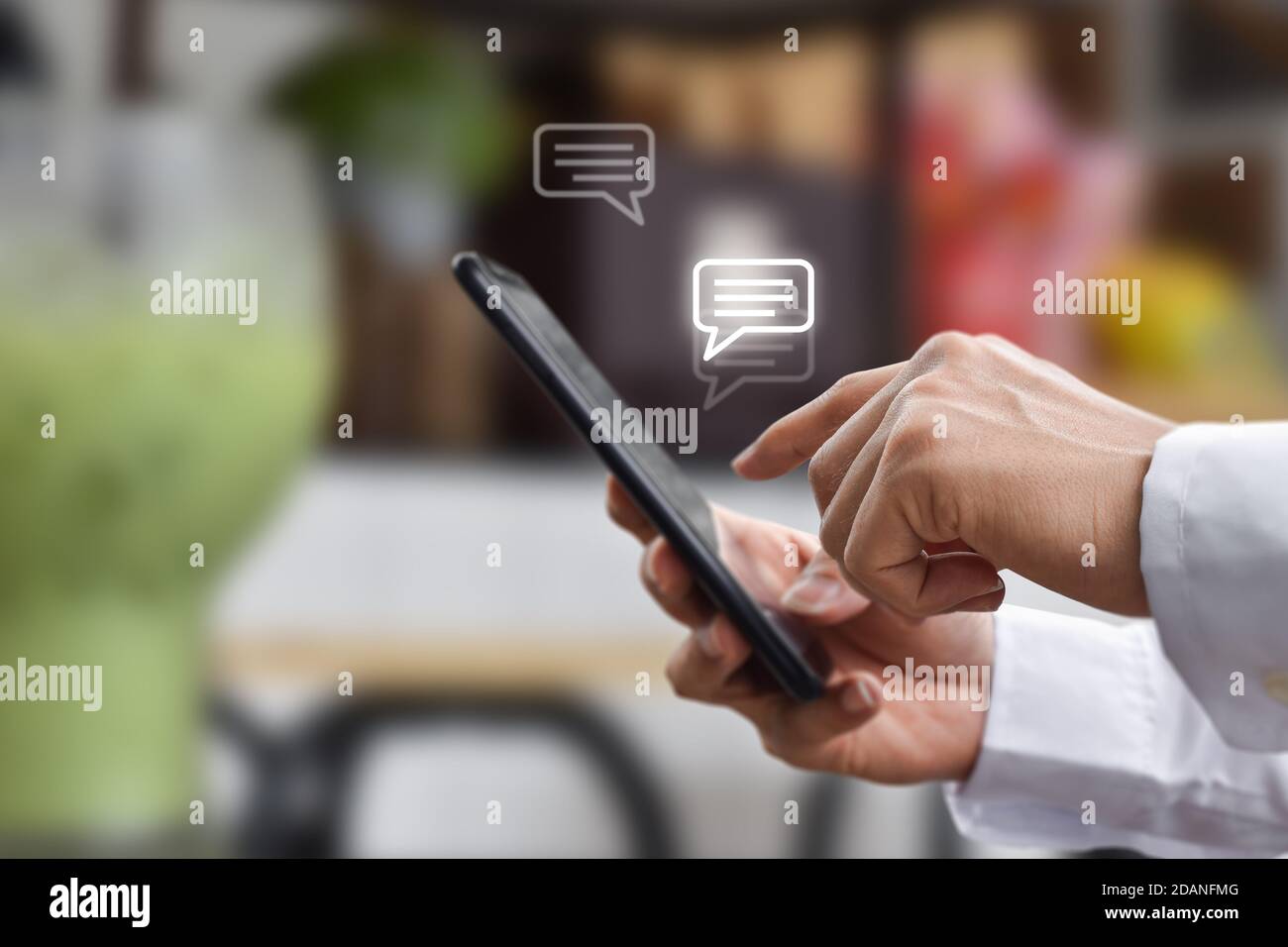 Hand using mobile phone typing, with chat icons. Social media and ...