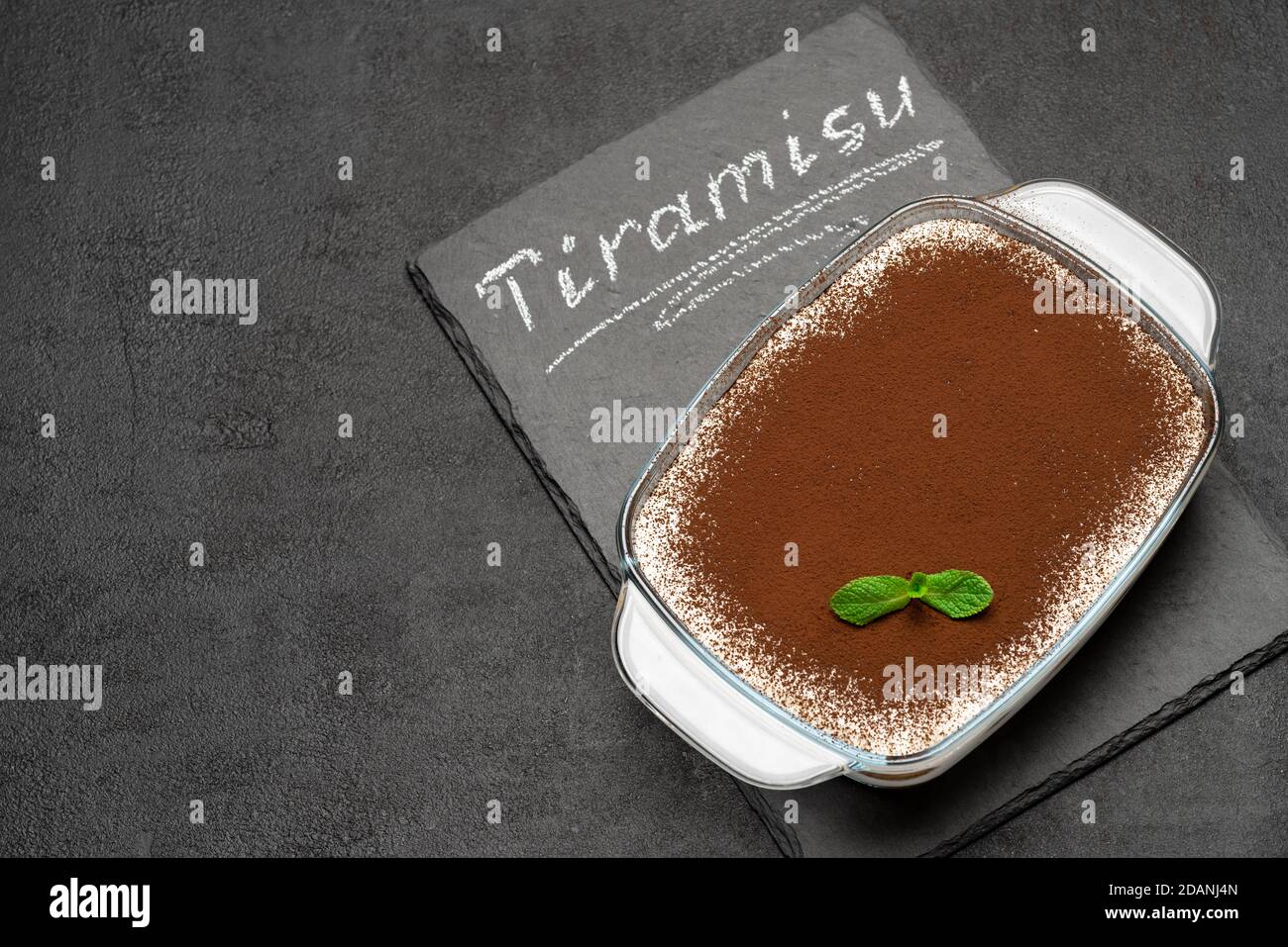 Traditional Italian Tiramisu dessert in glass baking dish on stone ...
