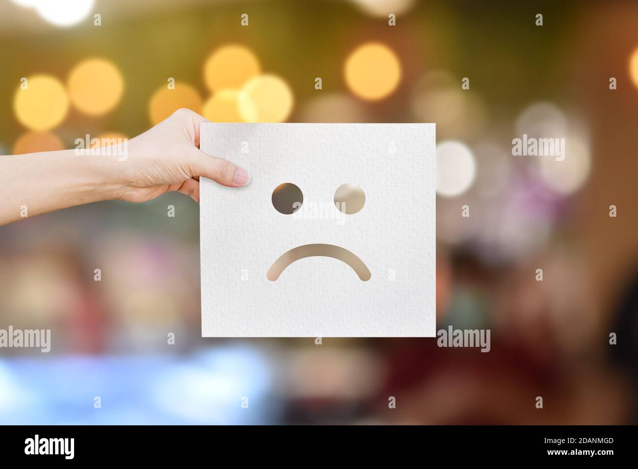 Hand holding white paper with unhappy face emoticons (perforated paper ...