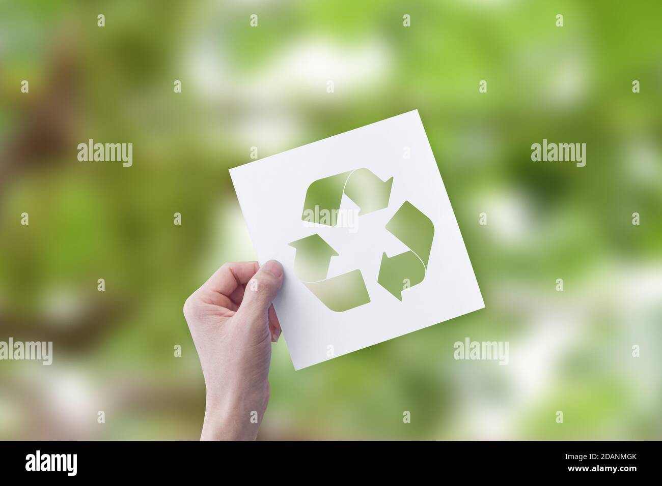 Hand holding cut paper with logo recycle over blur green nature ...