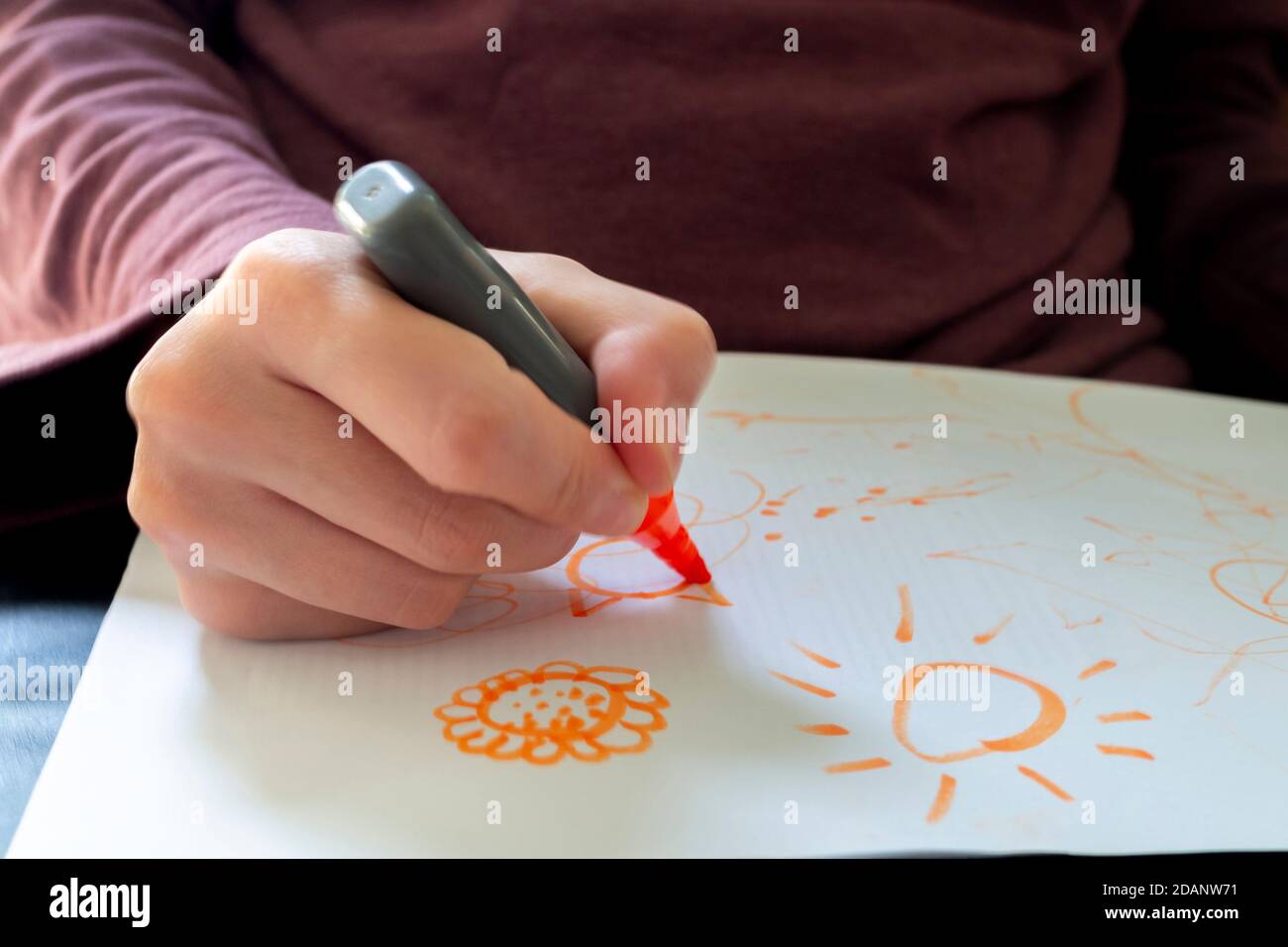 young teenager using an orange color highlighter pen to drawing flower ...