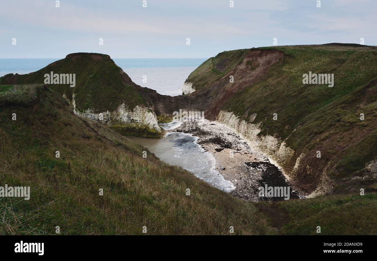 Sea and eroded chalk cliffs under bright autumnal sky at low dawn along ...