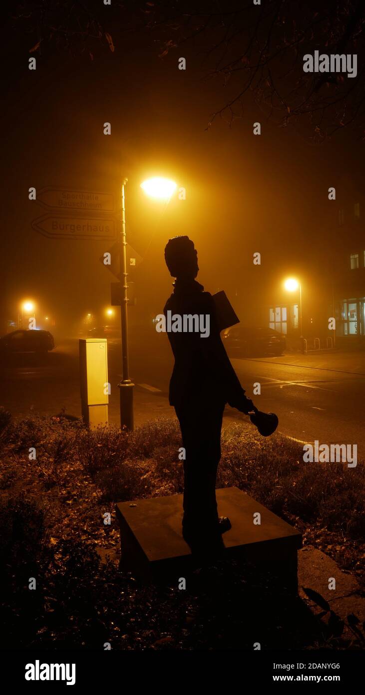 Statue of a man like a silhouette with a bell at night in the mists of ...