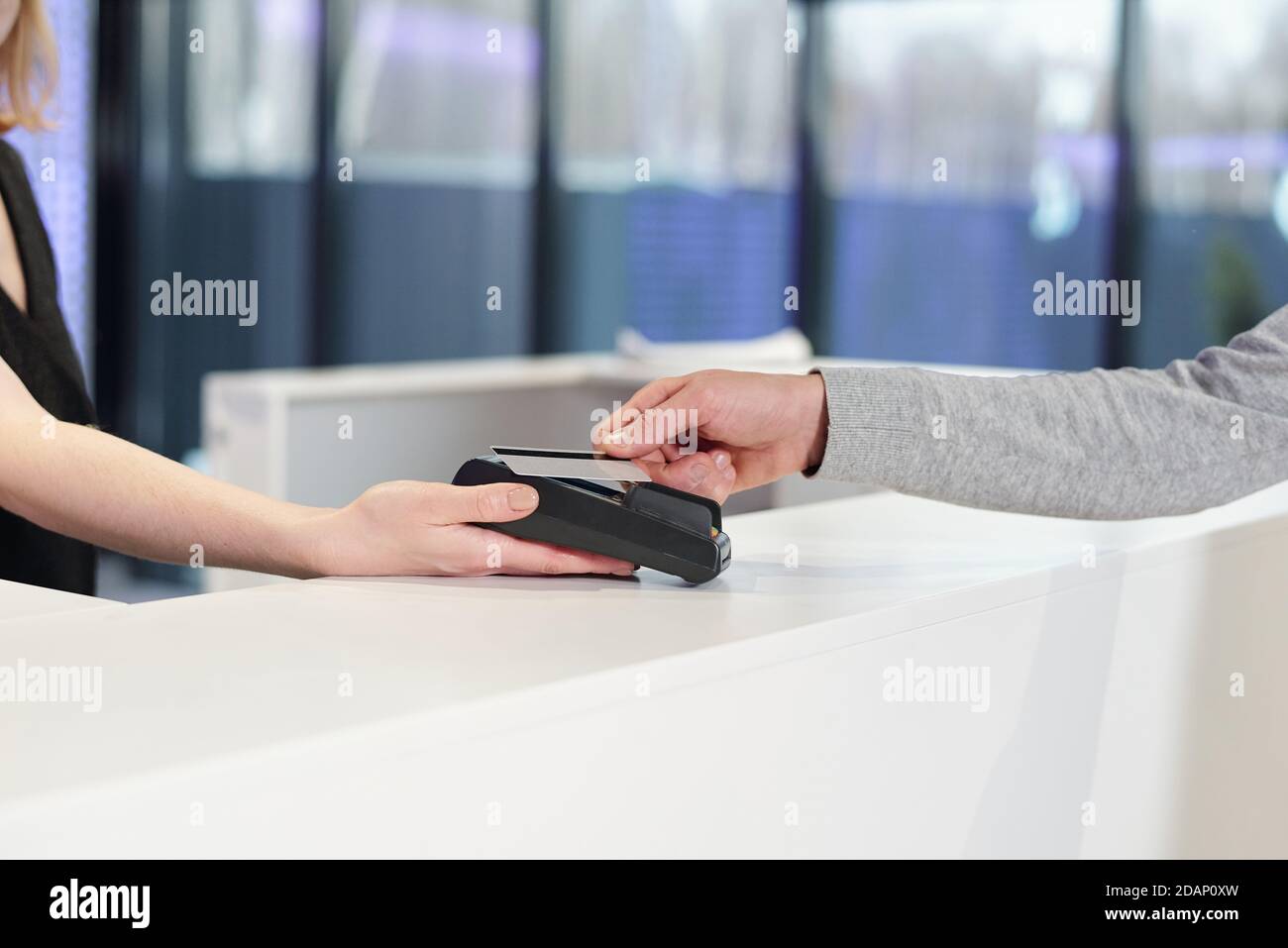 Young man holding smartphone over teminal held by female administrator ...