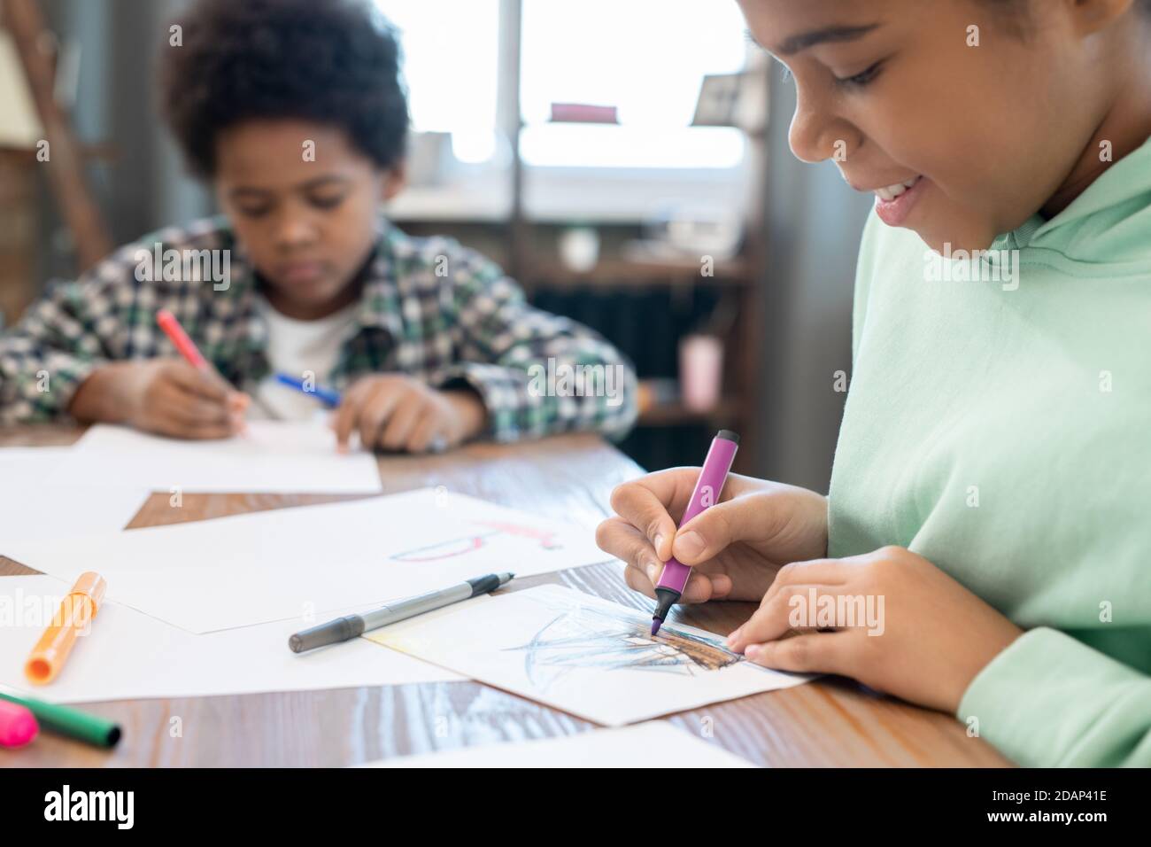 Diligent schoolgirl and her cute brother drawing with highlighters on ...