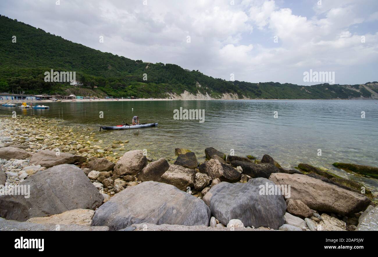 the bay of Portonovo of the Conero Riviera. A fisherman on the shore ...