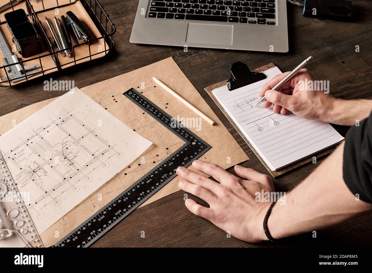 Hands of young male engineer or architect with ruler and pen making ...