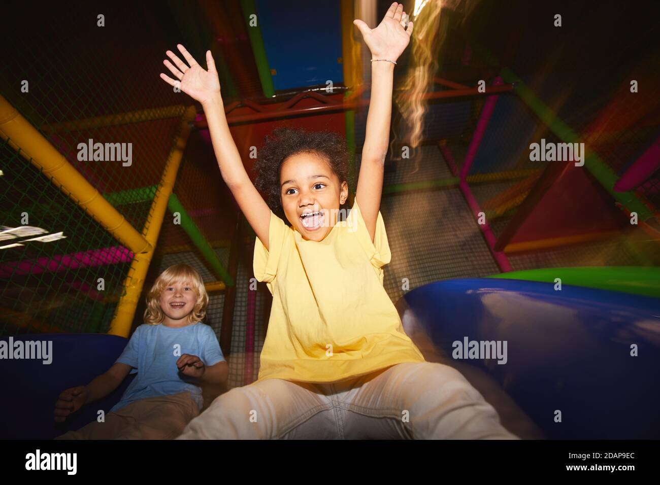 Excited children having fun on a slide together playing in ...