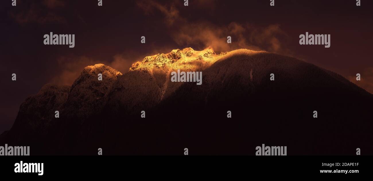 Dramatic sunset over fresh snow-covered mysterious, and moody mountains ...