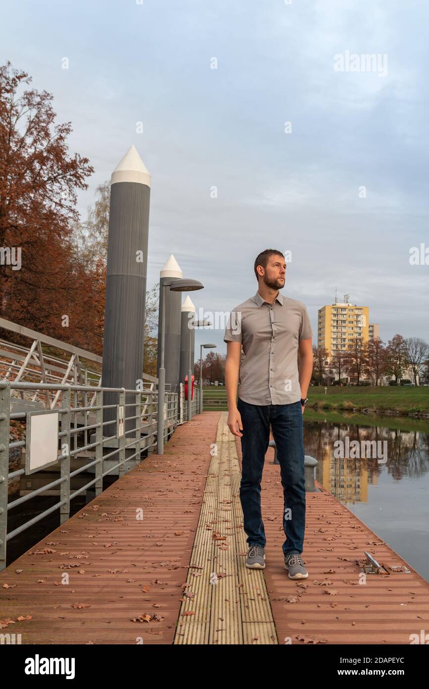 Portrait of young caucasian man walking on shipyard on Vltava river in ...