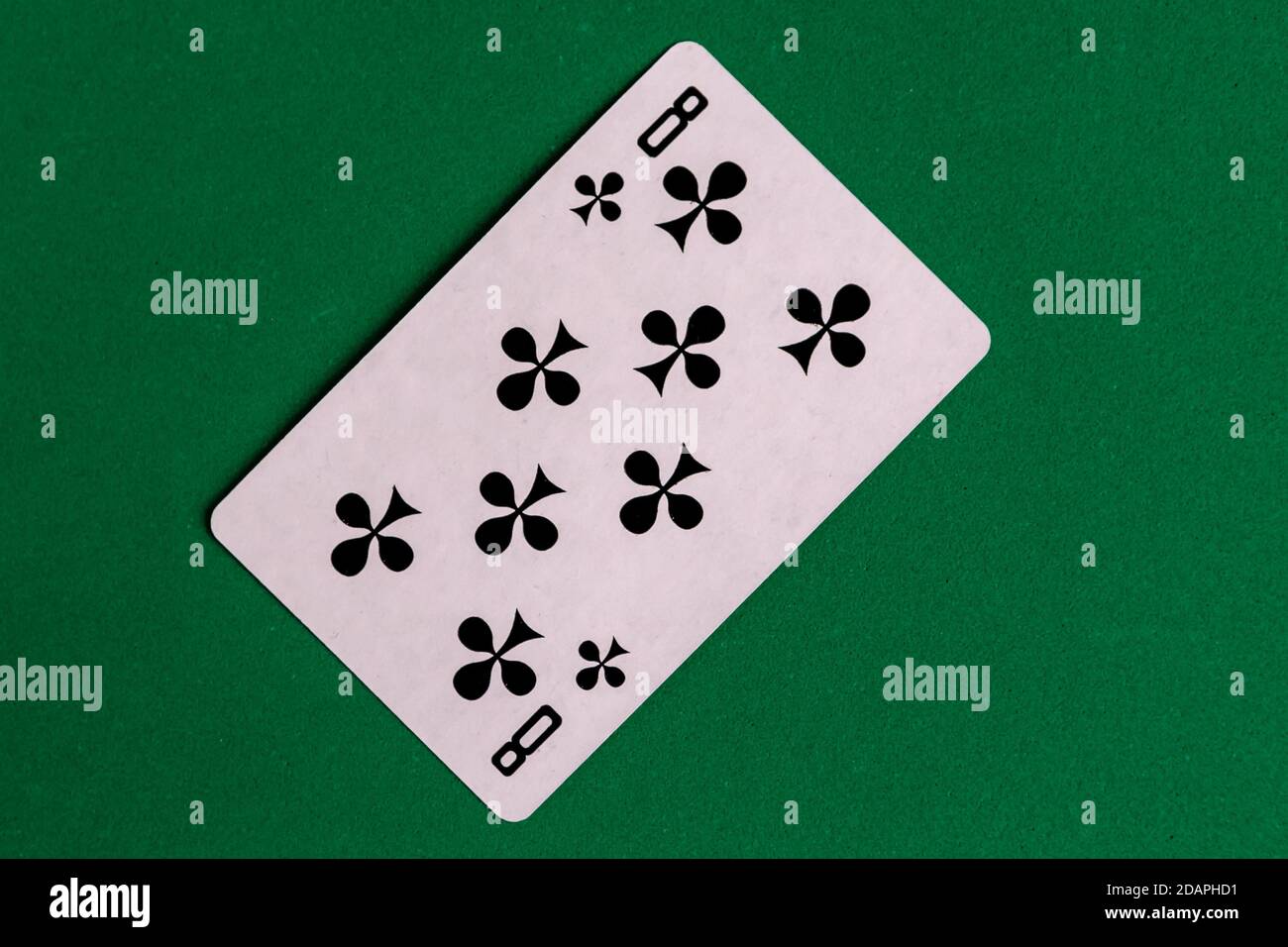 Eight of Club playing card, green background Stock Photo - Alamy