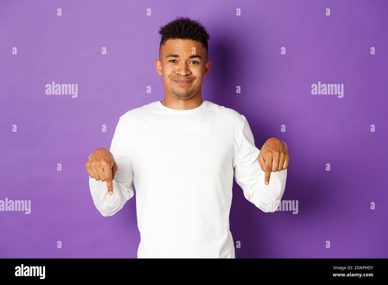 Image of skeptical african-american guy in white sweatshirt, looking ...