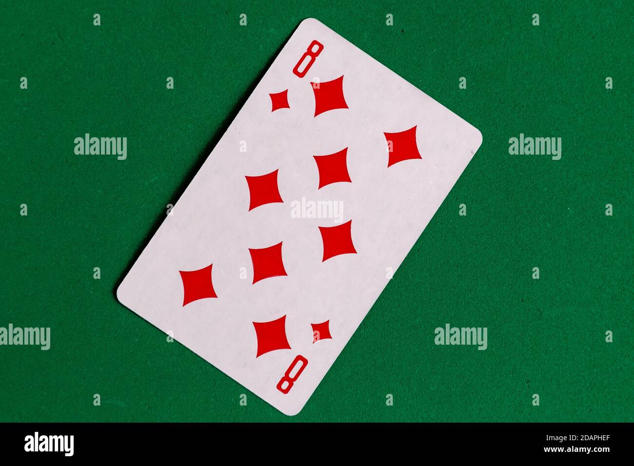 Eight of Diamond playing card, green background Stock Photo - Alamy