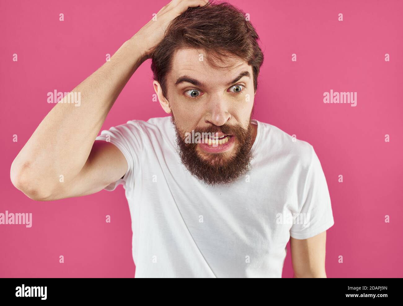 An angry man with a bushy beard bared his teeth against a pink ...