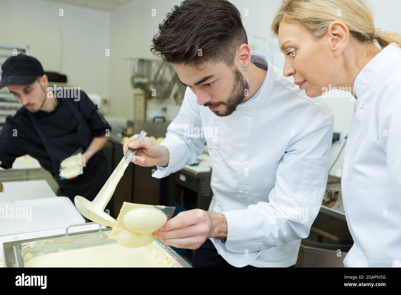 chocolatier apprentice pouring melted chocolate into egg mould Stock ...