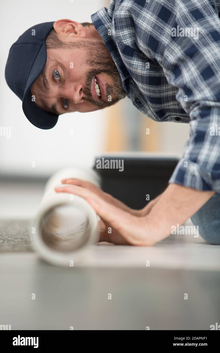 male worker unrolling carpet on floor at home Stock Photo - Alamy