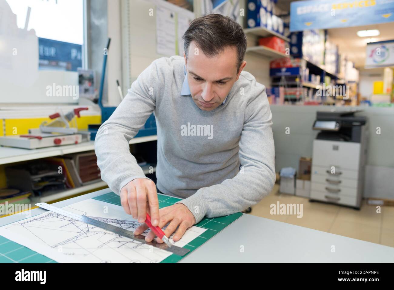 man cutting out scale drawing with a craft knife Stock Photo - Alamy