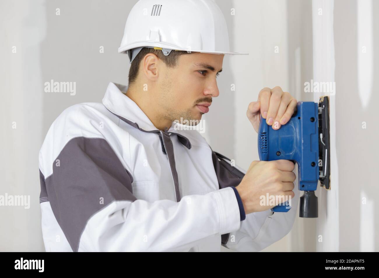 Young contractor sanding wall hi-res stock photography and images - Alamy