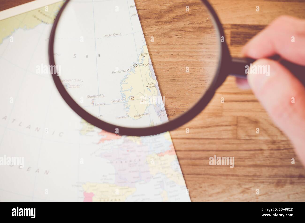 Overhead shot of a map as seen through a magnifying glass on a wood ...