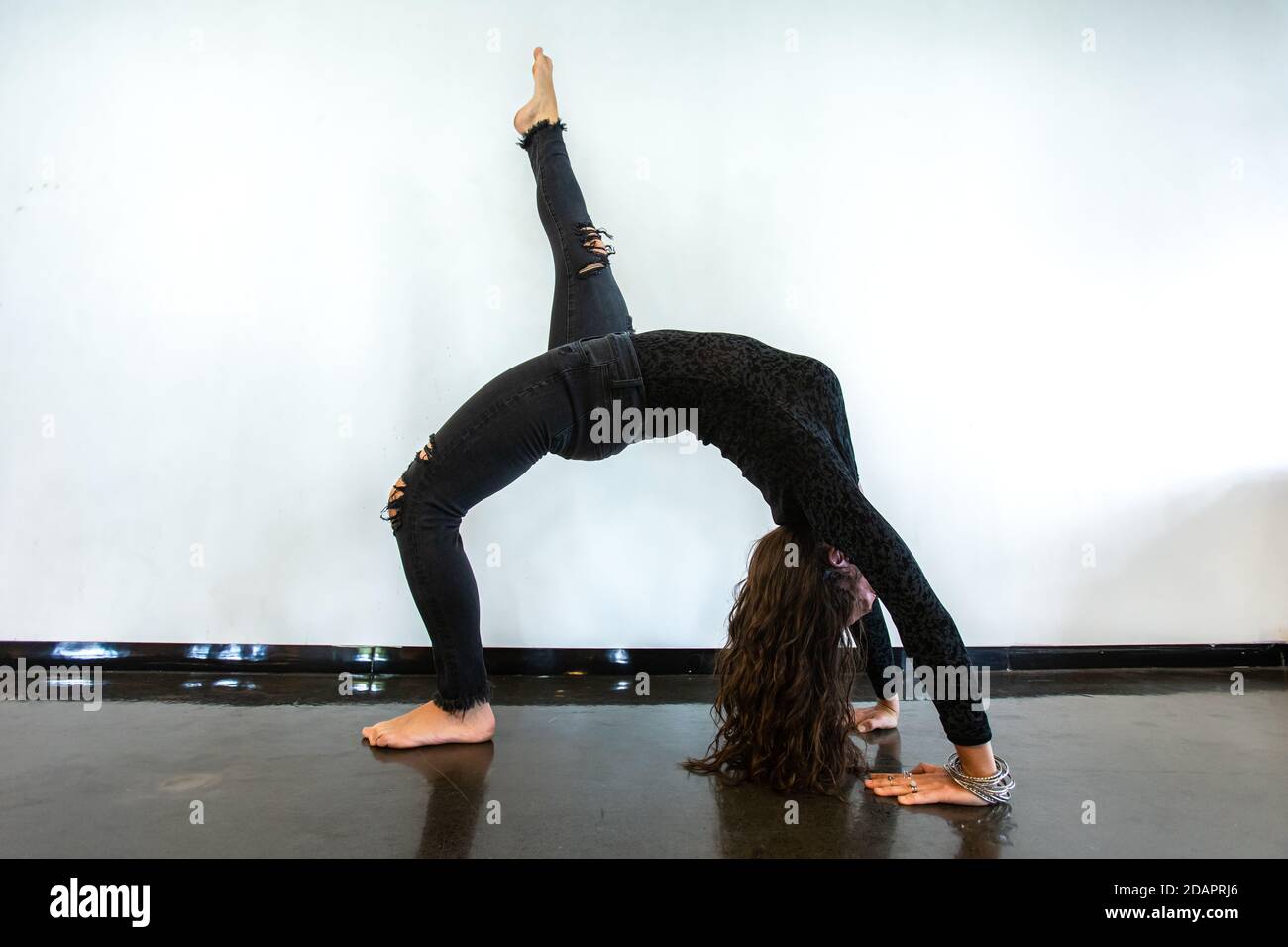 A side profile view of a flexible woman seen in a one legged upward bow ...