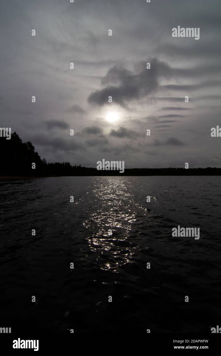 Dark water with sun and clouds Stock Photo - Alamy