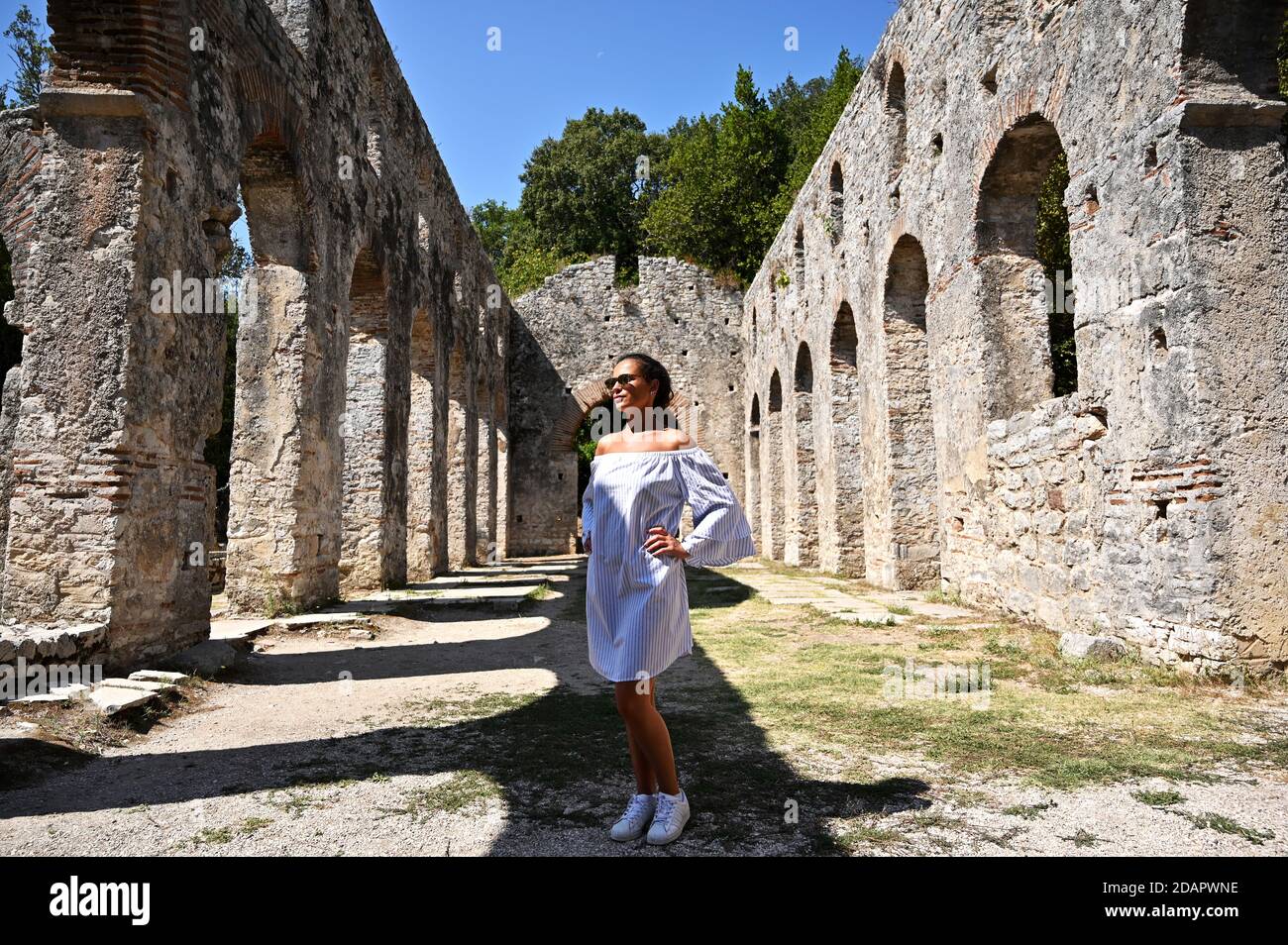 Young girl exploring an ruins of ancient city of Butrint.Olive-shaded ...