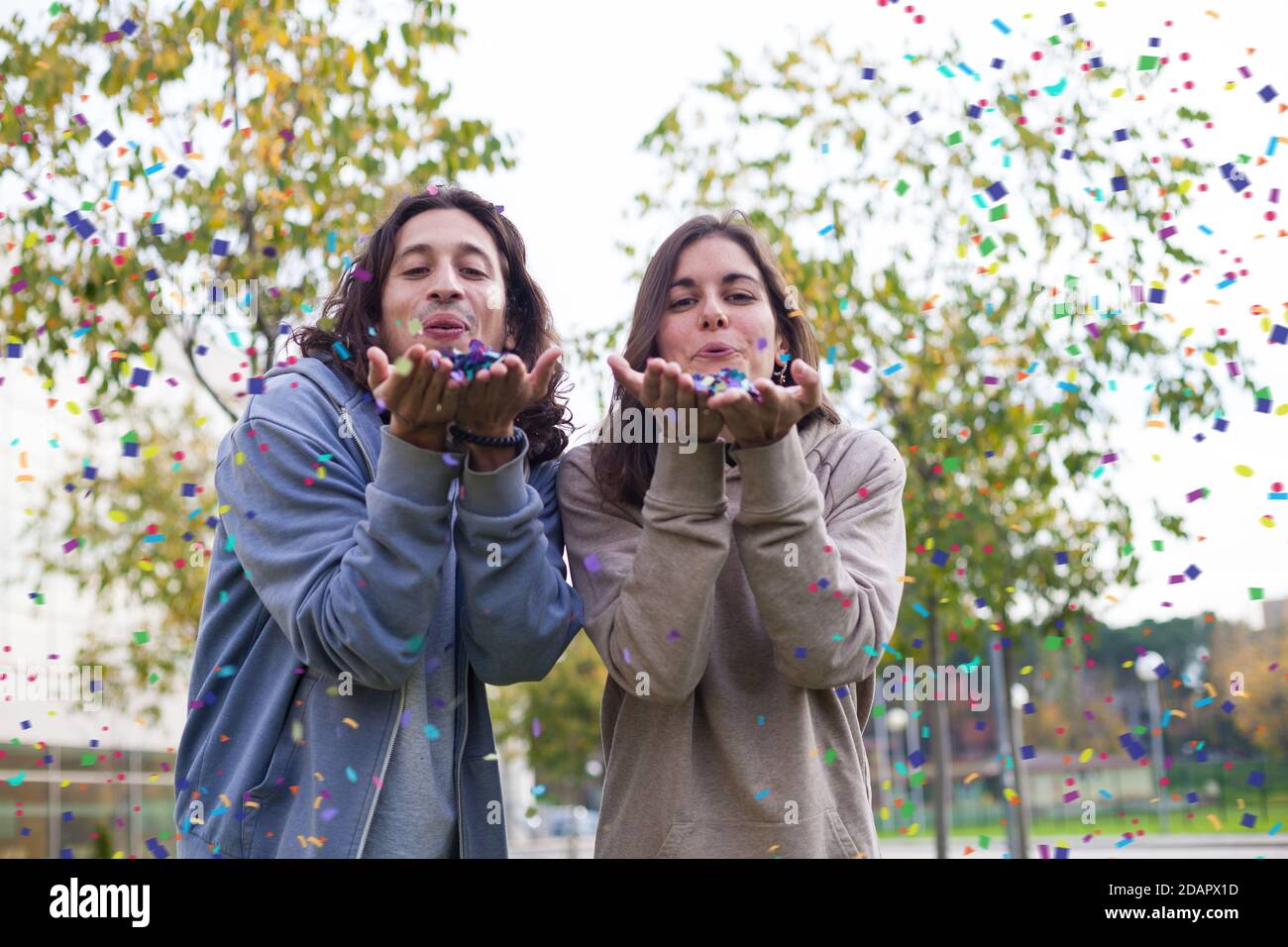 two young friends blowing confetti from hands. Friends celebrating ...