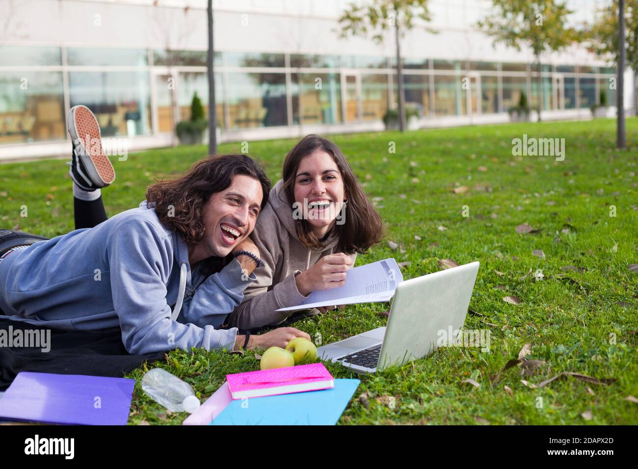 two happy university students studying outdoor at the school campus ...