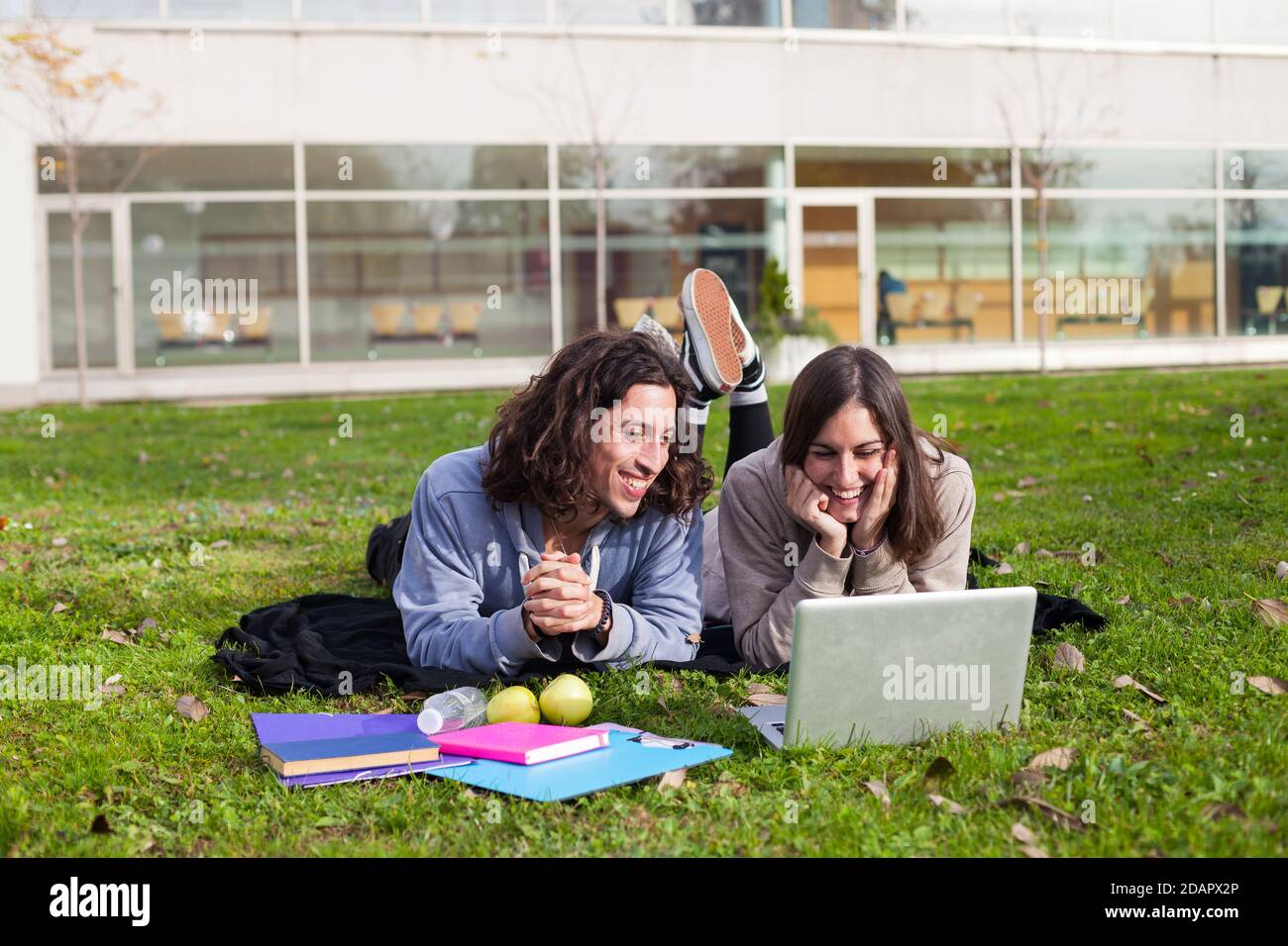 two happy university students studying outdoor at the school campus ...