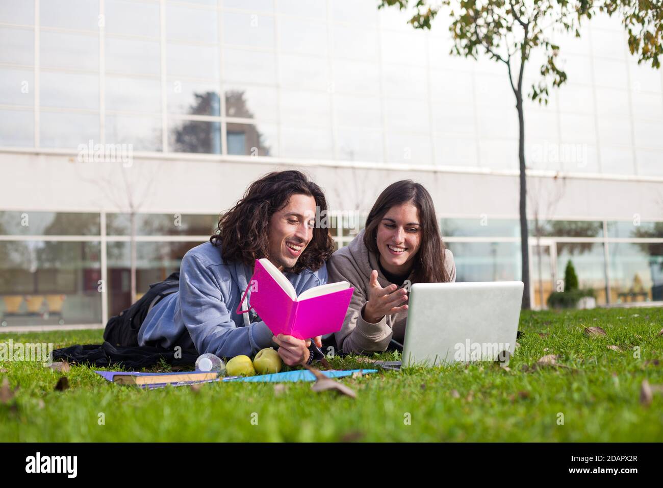 two happy university students studying outdoor at the school campus ...