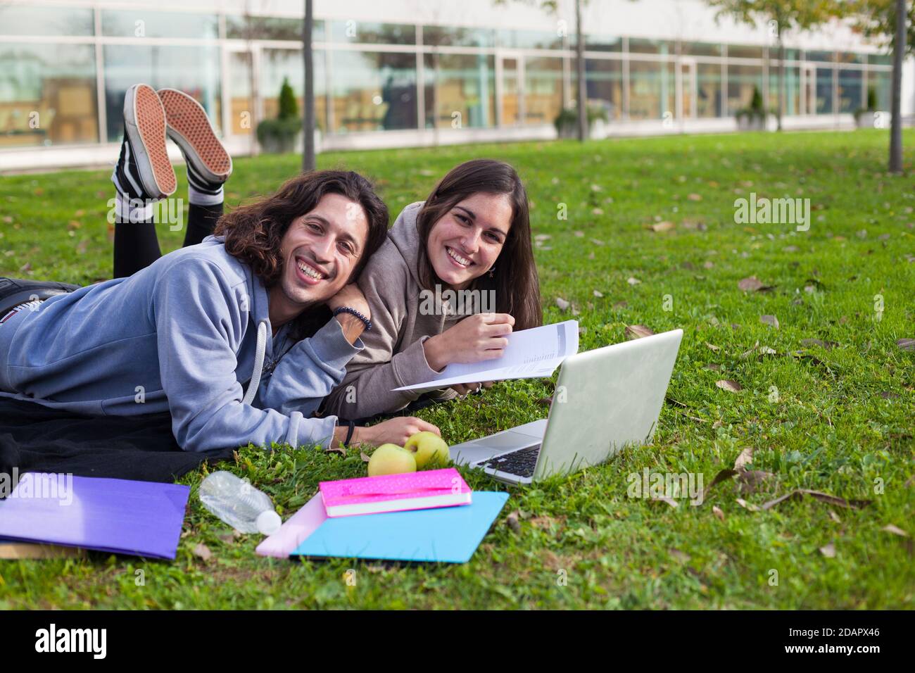 two happy university students studying outdoor at the school campus ...