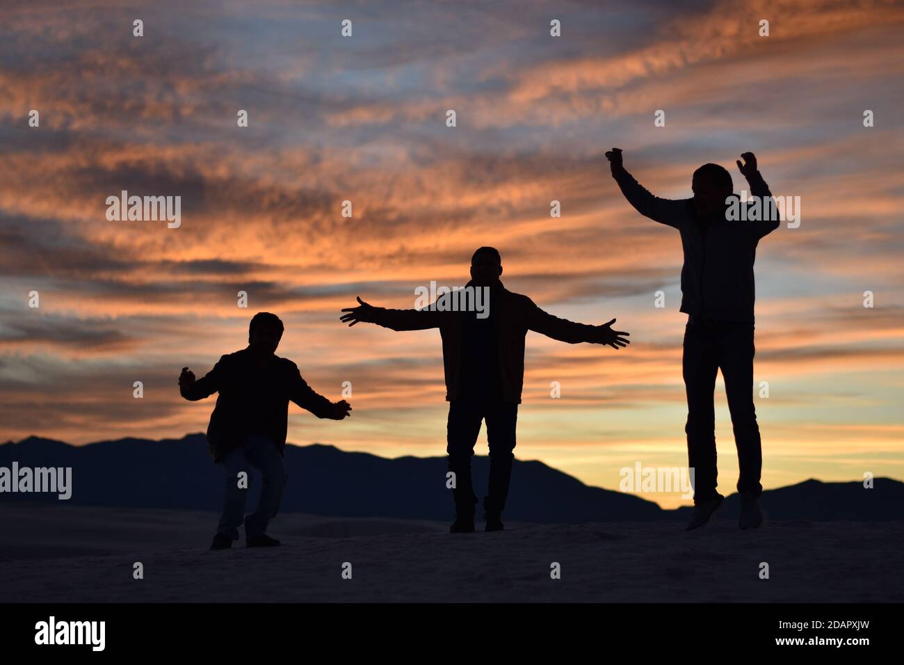 Group of three happy friends jumps at sunset time on background ...