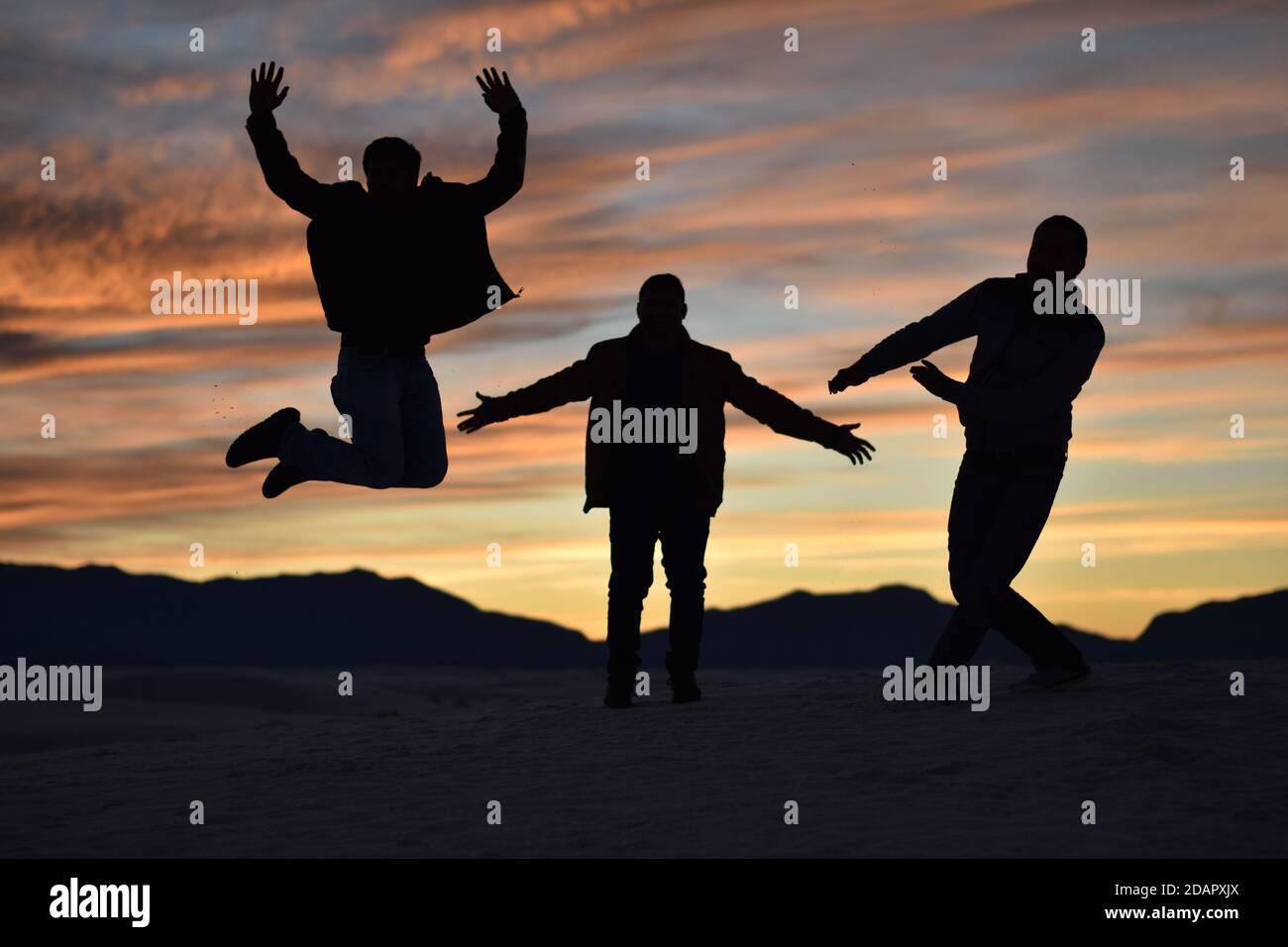 Group of three happy friends jumps at sunset time on background ...