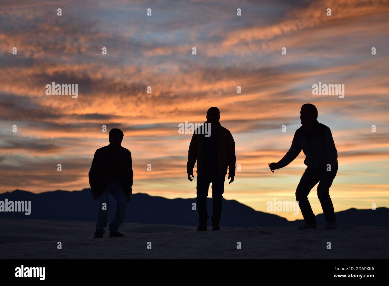 Group of three happy friends jumps at sunset time on background ...