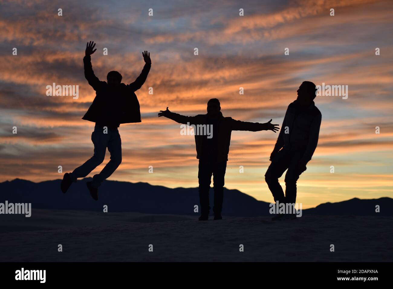 Group of three happy friends jumps at sunset time on background ...