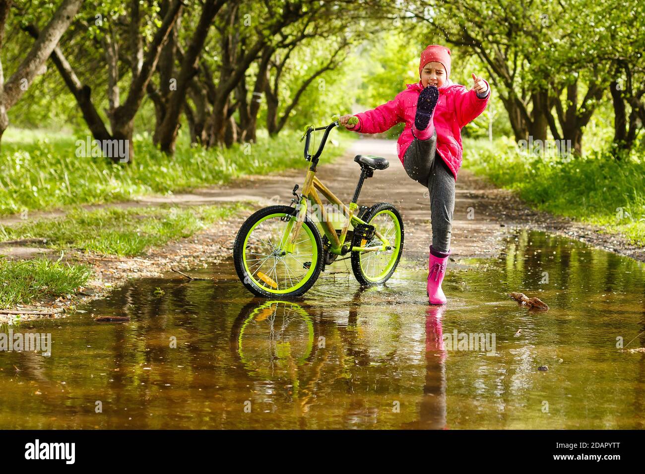 little girl riding bike in water puddle Stock Photo - Alamy