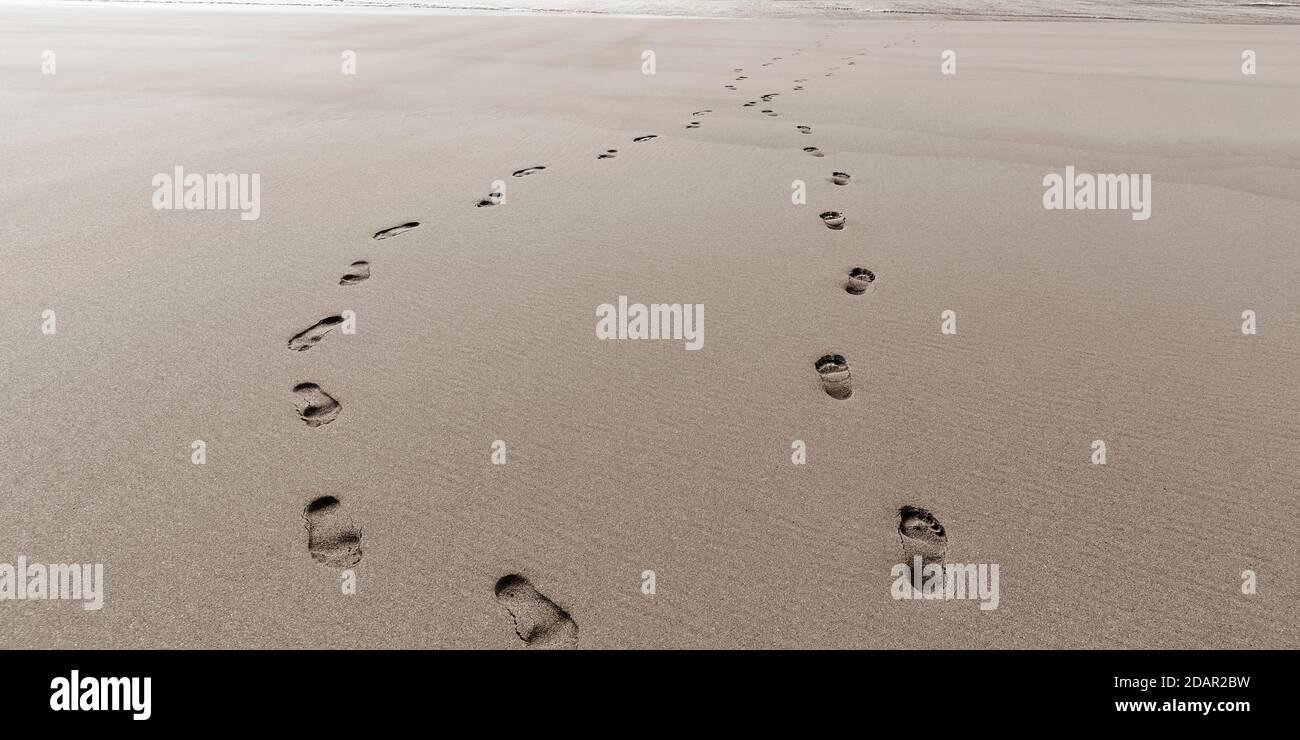 Two footprints in the sand, on the beach, paths crossing, symbolic ...