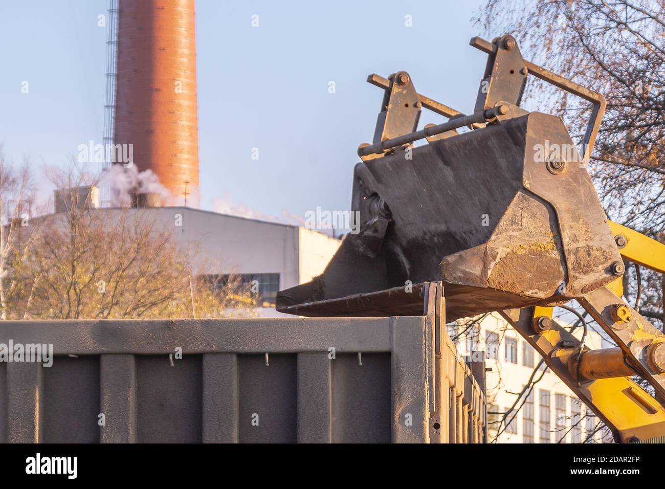 loader bucket loads into the back of the truck Stock Photo - Alamy