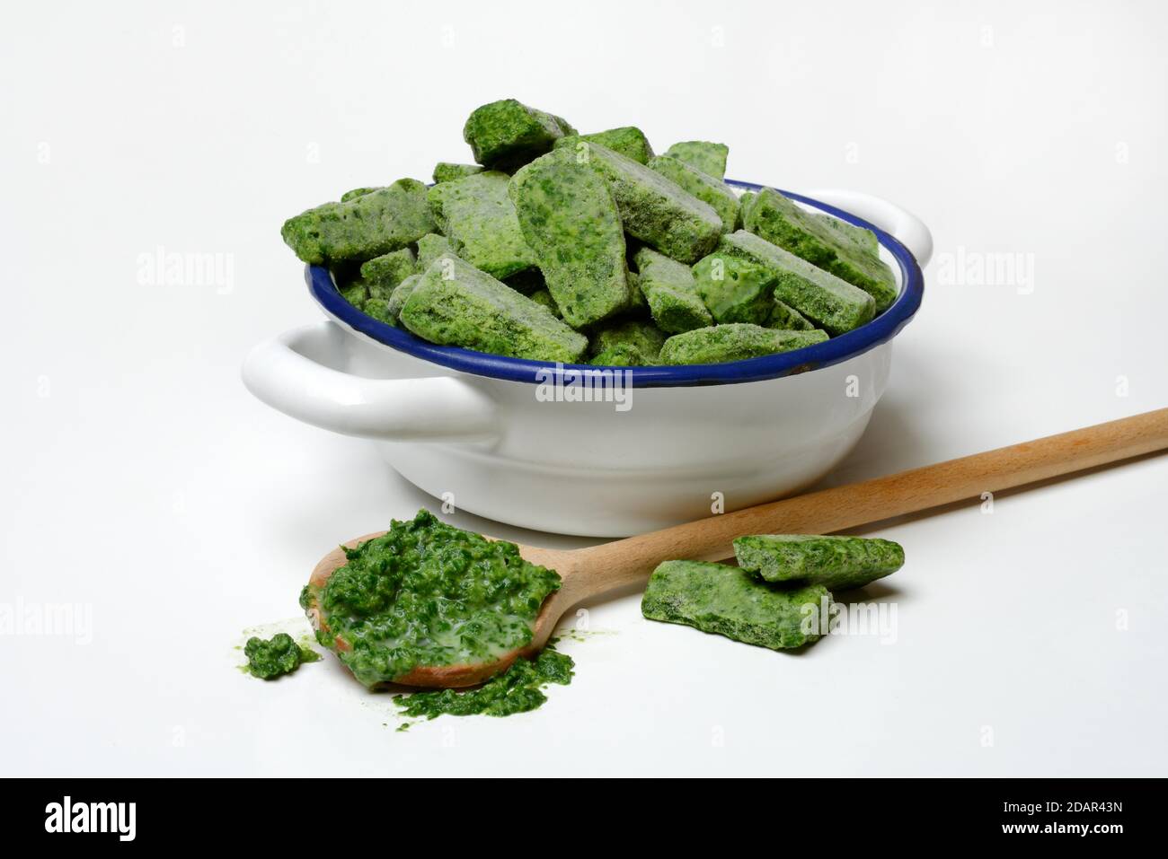 Portioned, frozen creamed spinach in bowl and defrosted spinach in ...